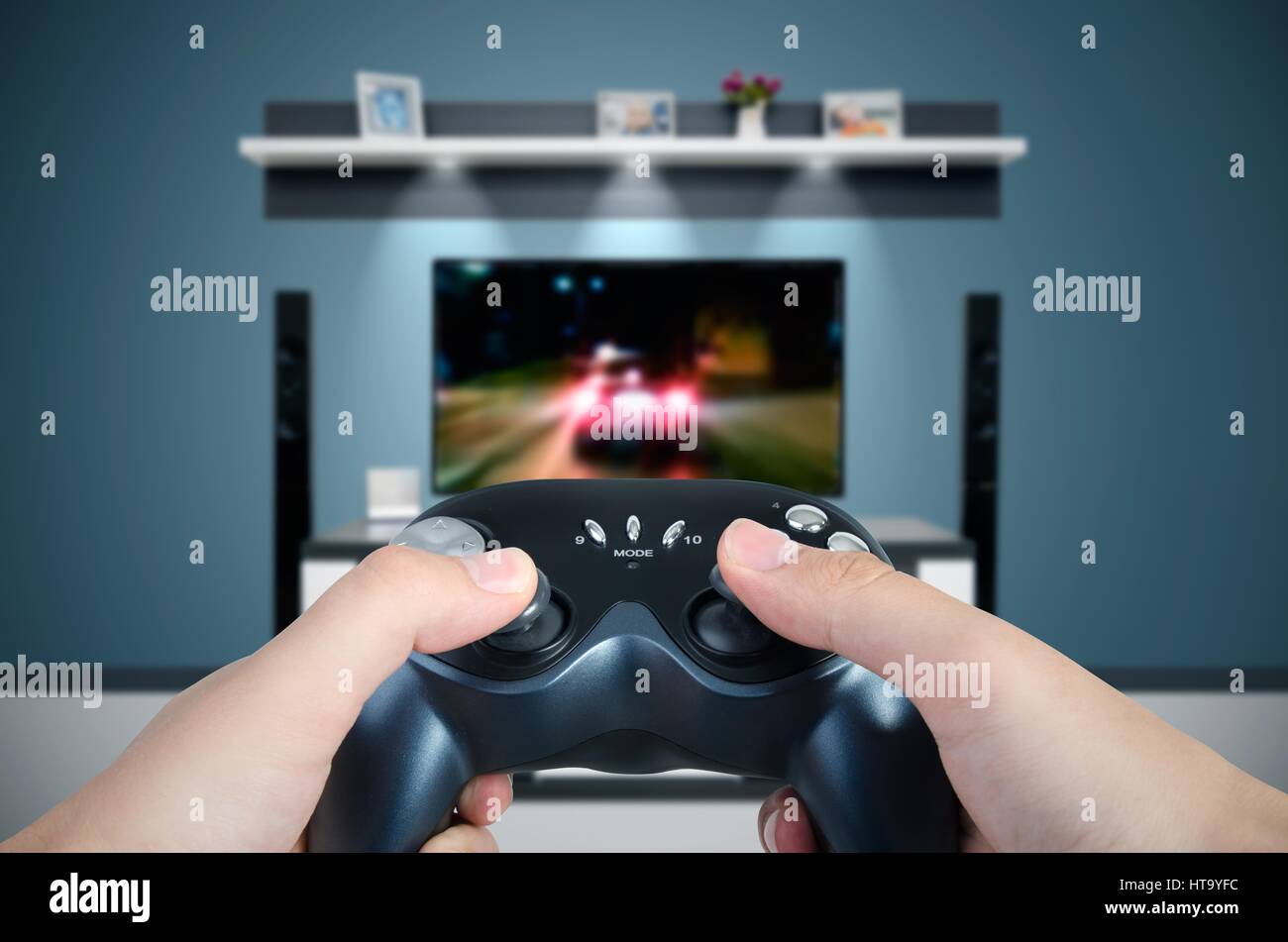 Hands hold the game controller. Man playing a car racing on TV in a ...