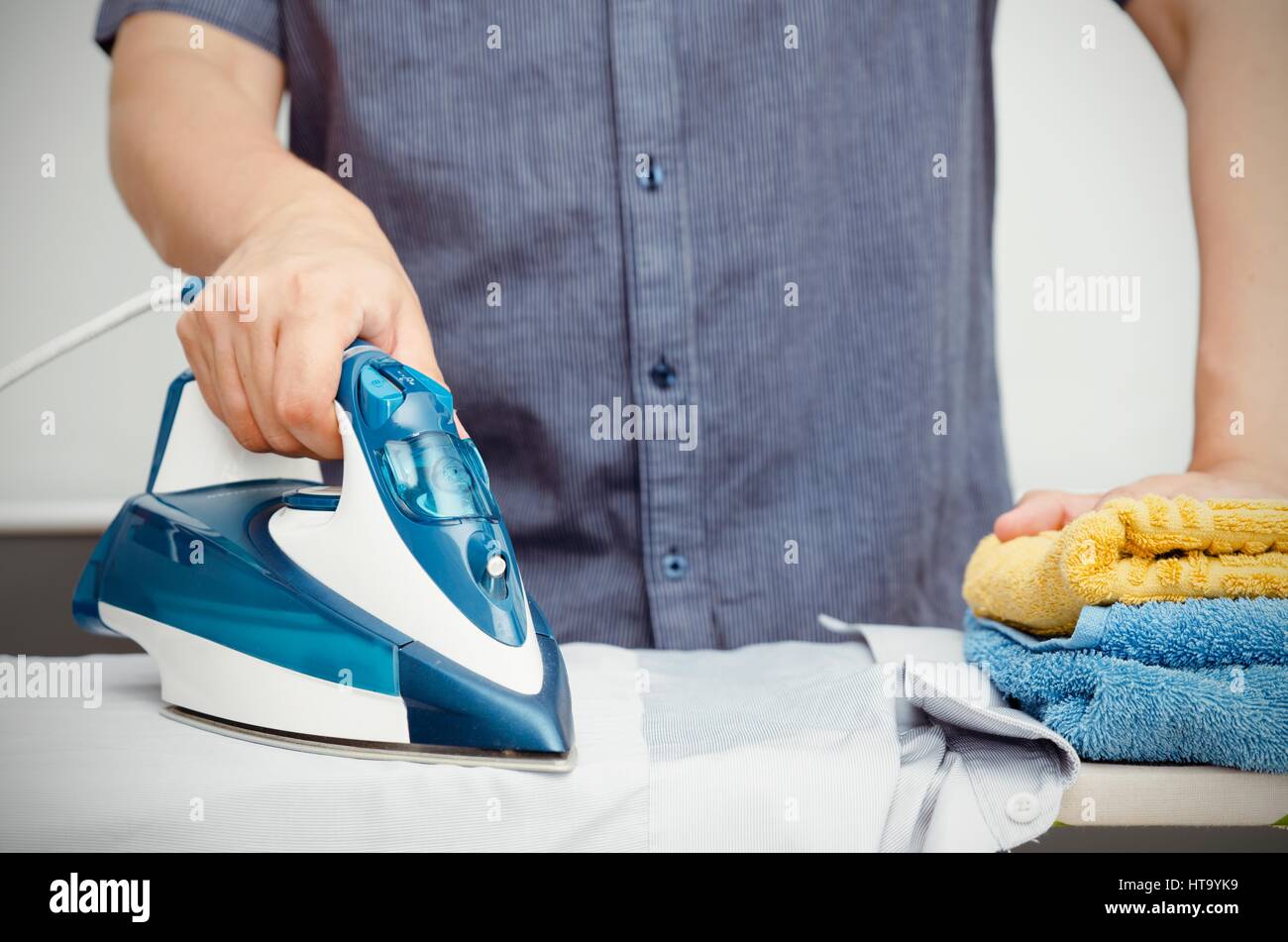 Man irons clothes on ironing board with steaming blue iron Stock Photo ...