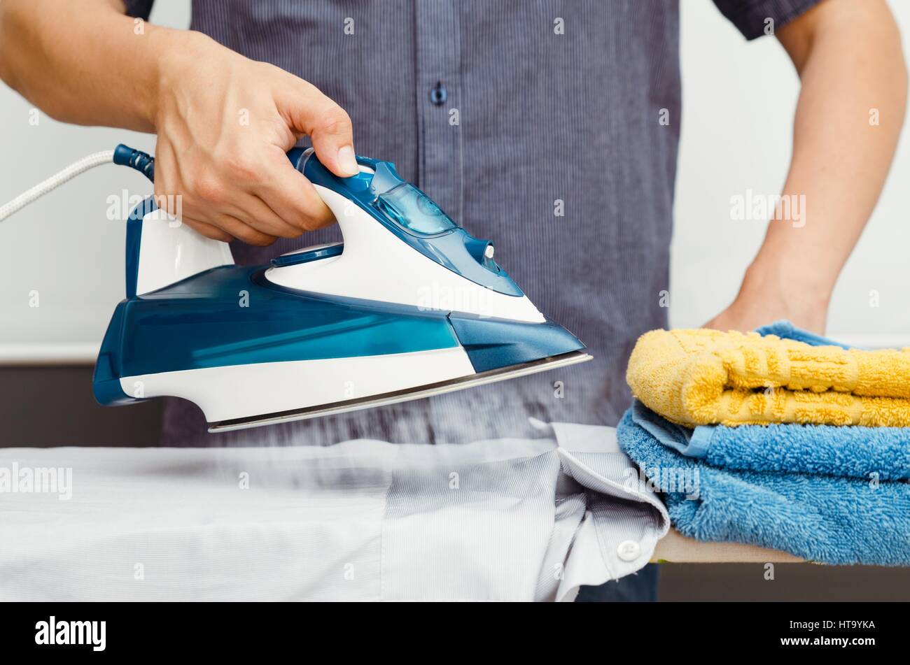 Man irons clothes on ironing board with blue steaming iron Stock Photo ...