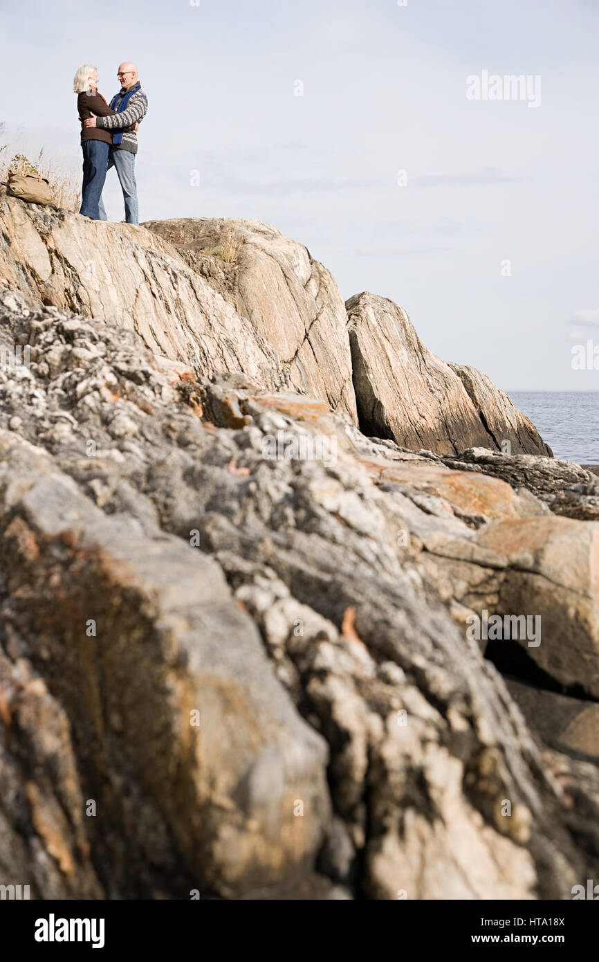 Mature couple hugging on rocks Stock Photo - Alamy