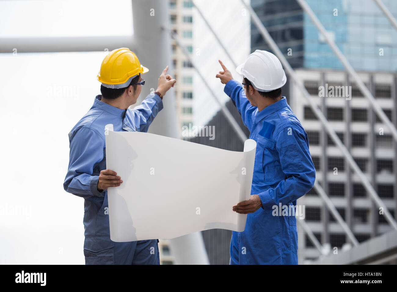 Engineer and Foreman outside office with yellow, white helmet point to ...