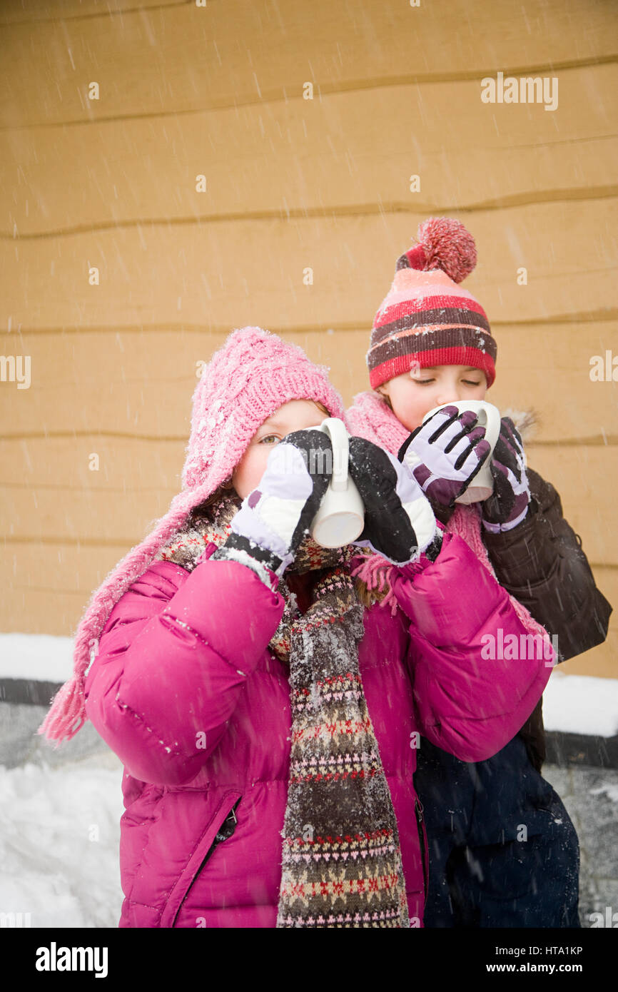 Girls drinking hot drink in snow Stock Photo - Alamy