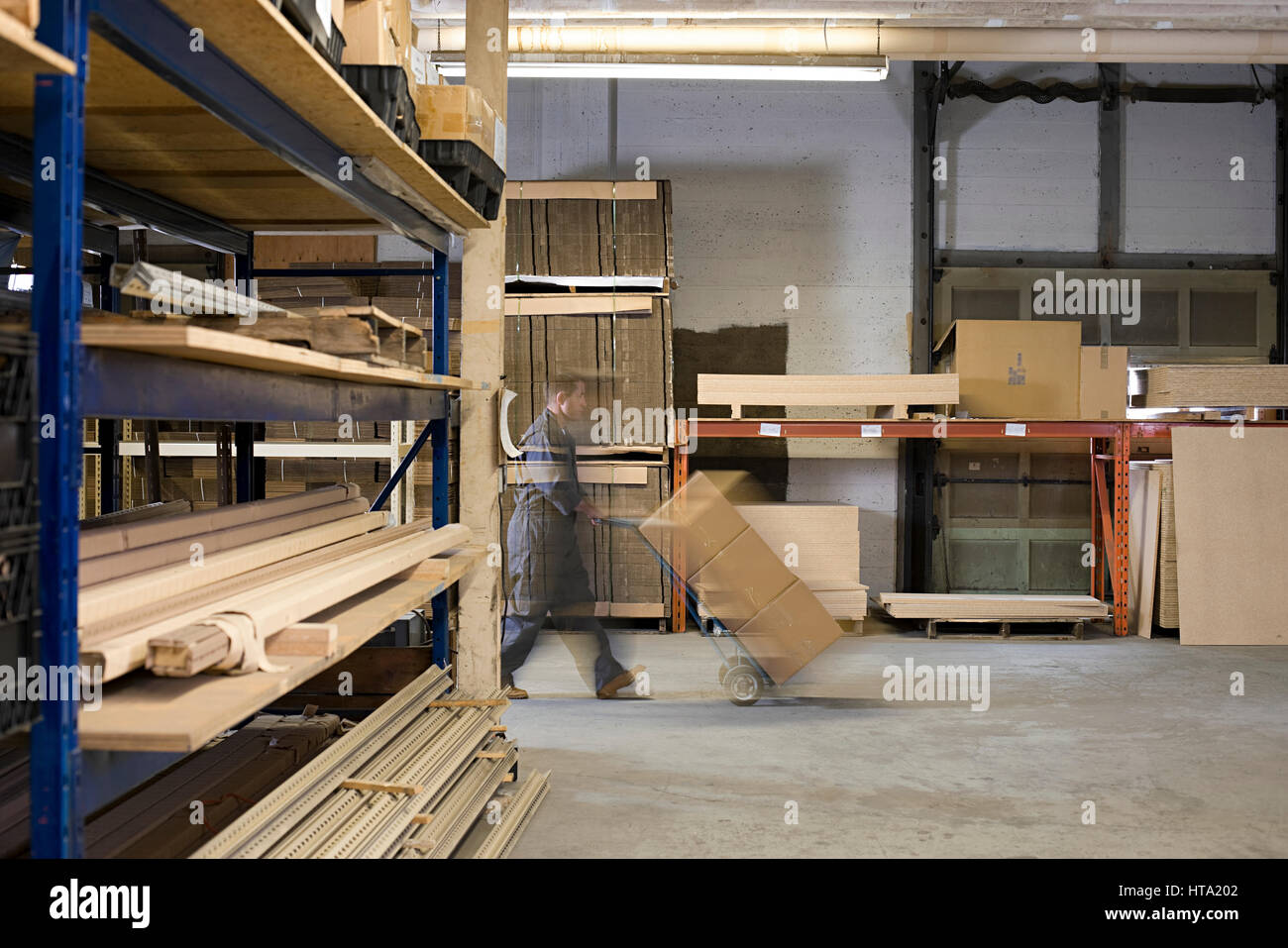 Man pushing boxes in warehouse Stock Photo - Alamy