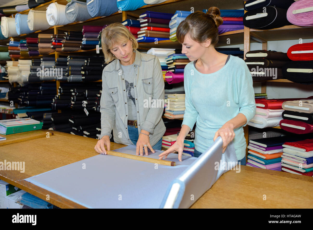 Women measuring length of material Stock Photo - Alamy