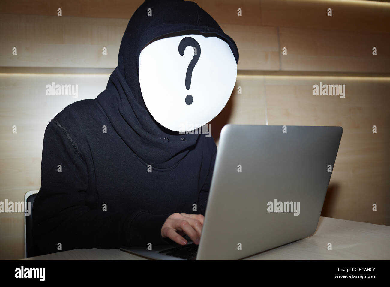 Waist-up portrait of anonymous hacker in black hoodie and white mask ...