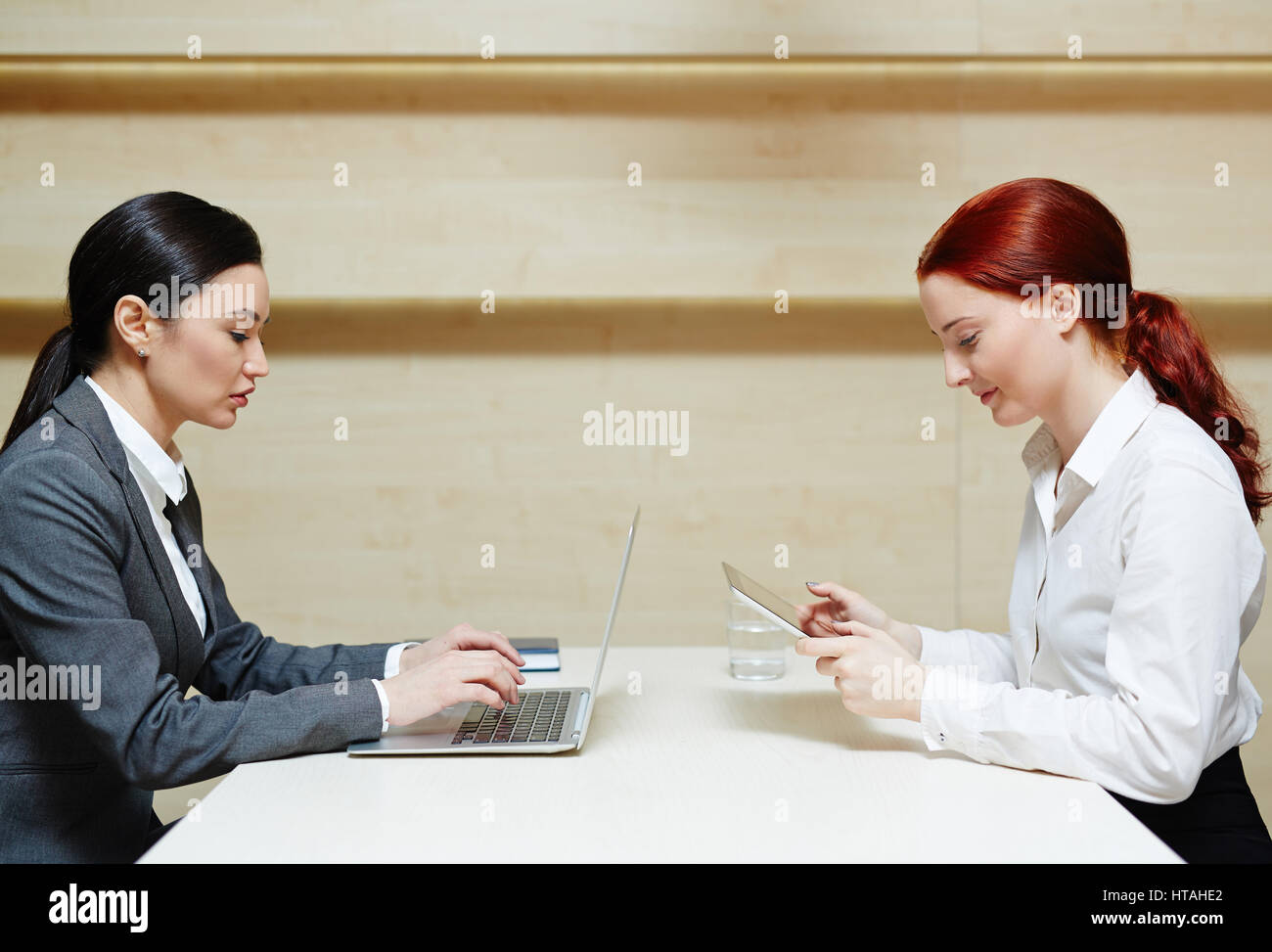 Smiling businesswomen sitting desk working hi-res stock photography and ...