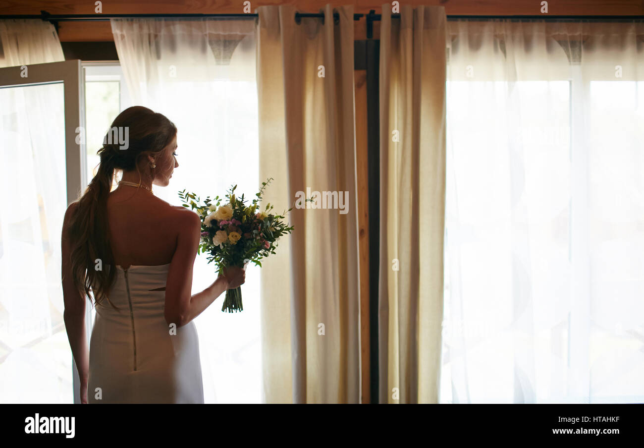 Back of bride with bouquet standing by window Stock Photo - Alamy