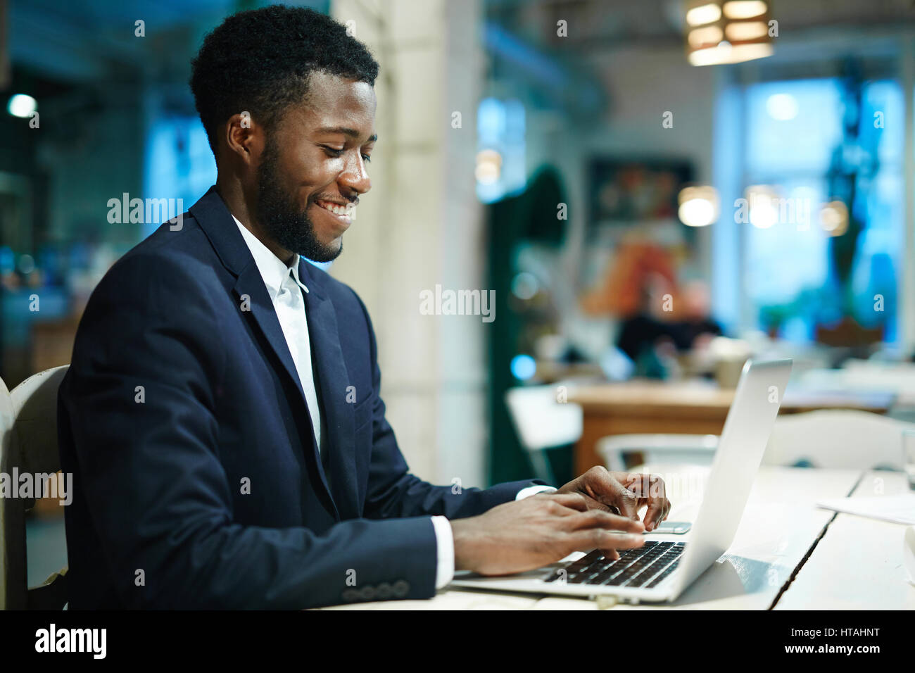 Smiling employee with laptop entering data Stock Photo - Alamy