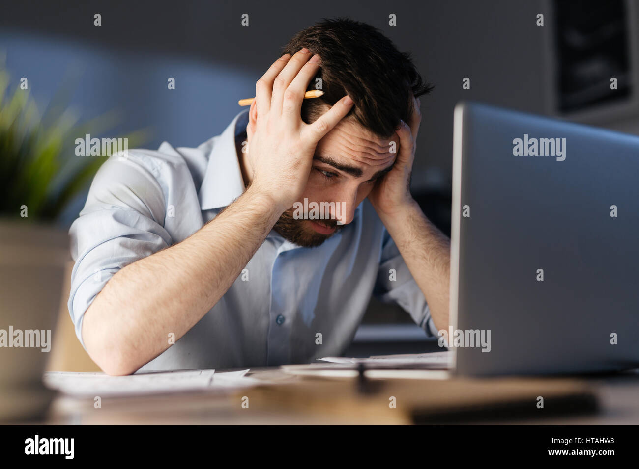 Frustrated man looking at laptop display with his head in hands Stock ...