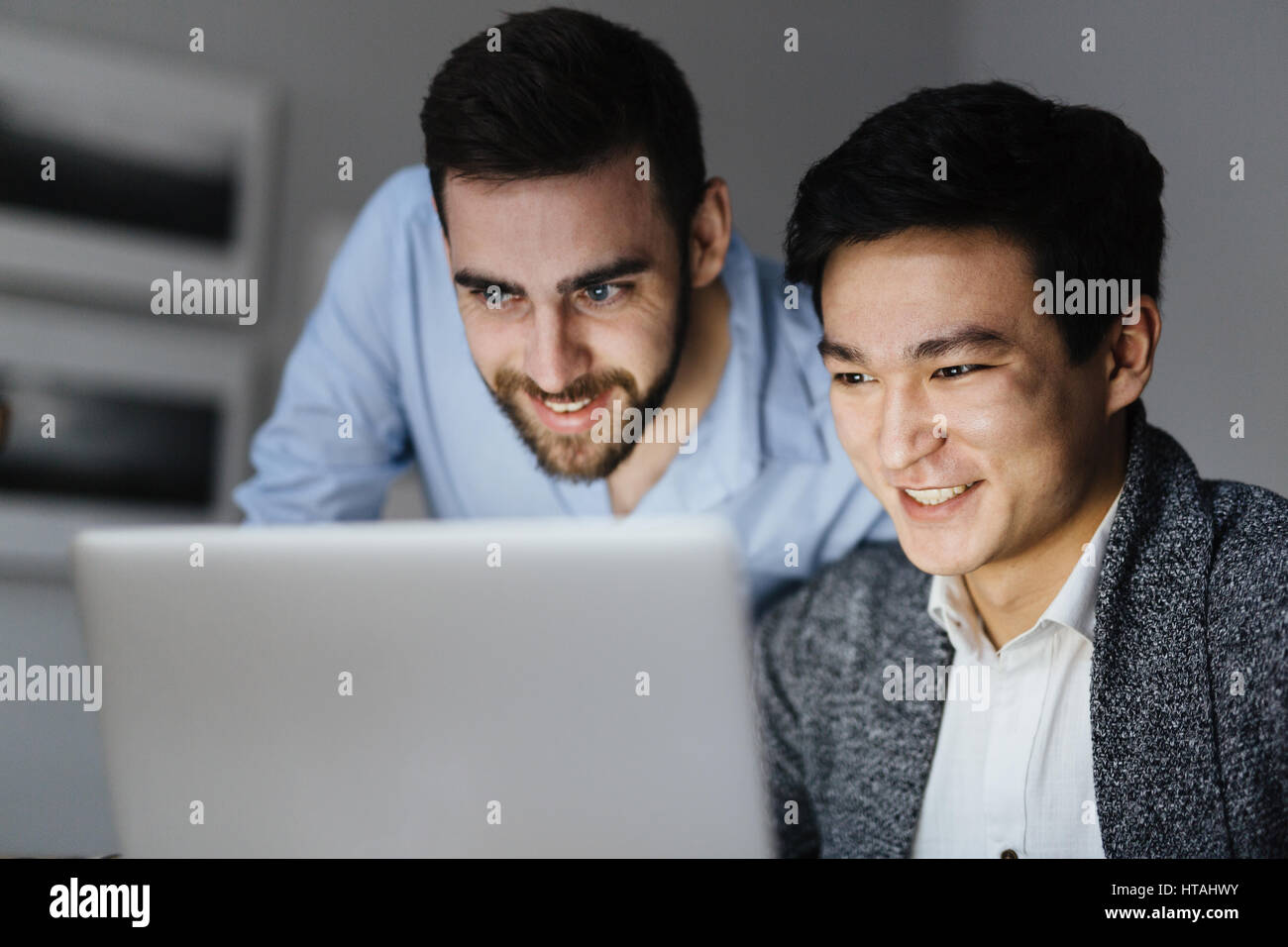 Creative men reading data in laptop with smiles Stock Photo - Alamy
