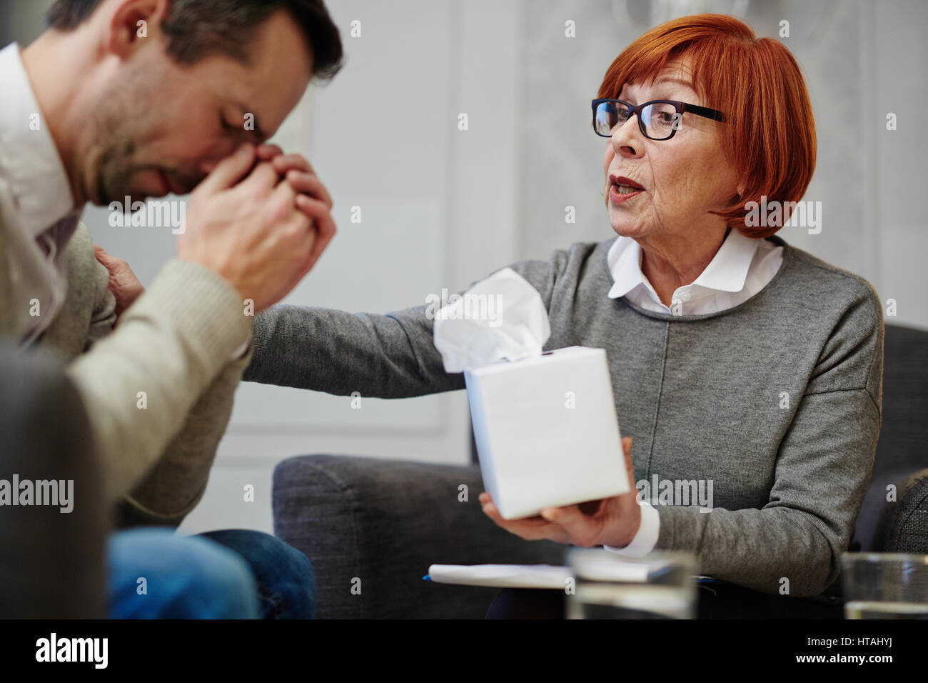 Psychologist offering paper tissues to suffering man Stock Photo - Alamy