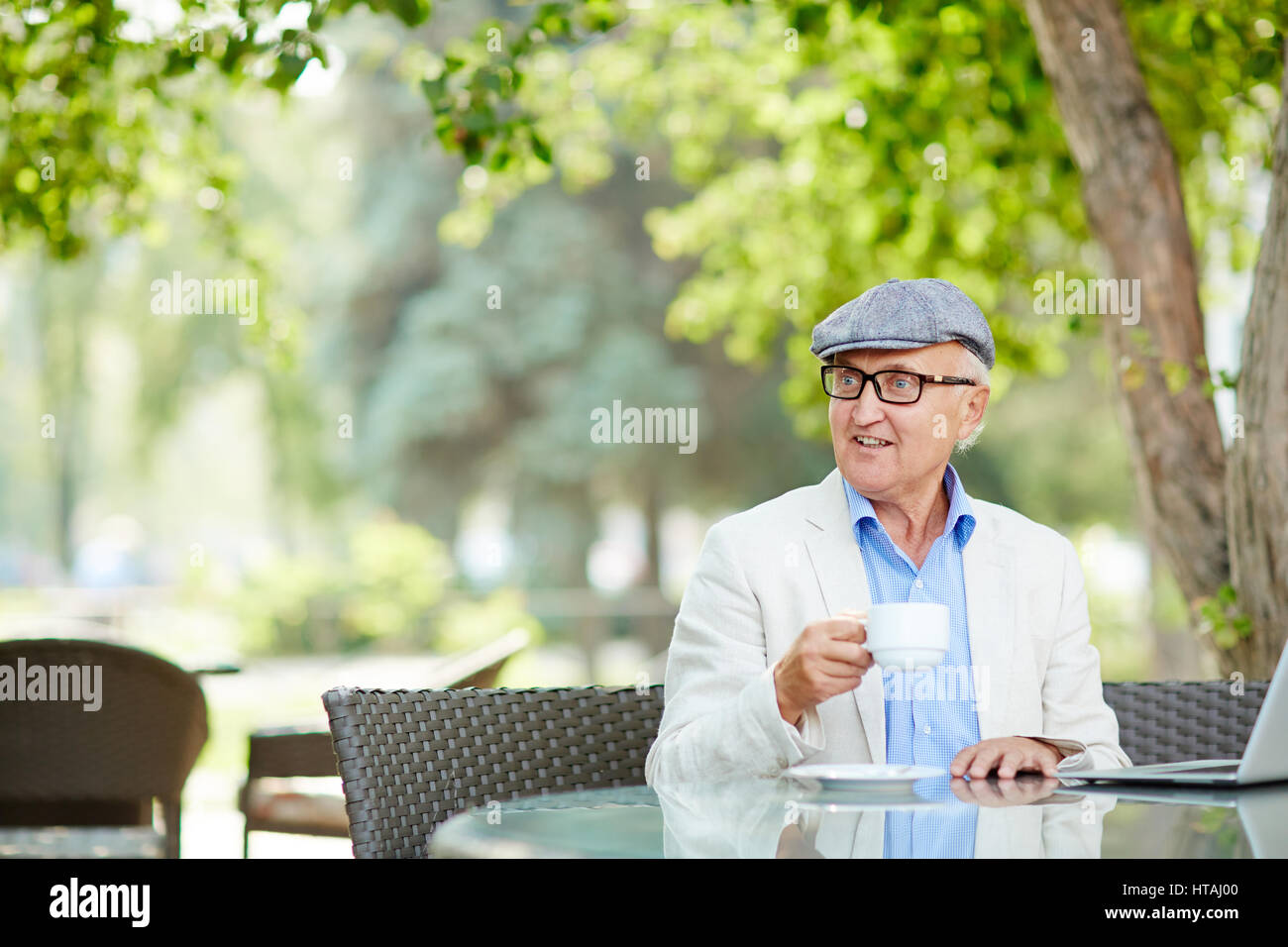 Portrait of lively senior man wearing cap and black rim glasses ...