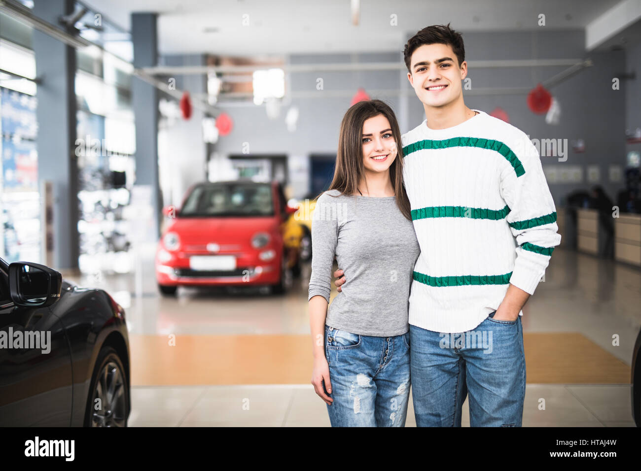 Smiling couple standing in front of a car at new car Stock Photo - Alamy