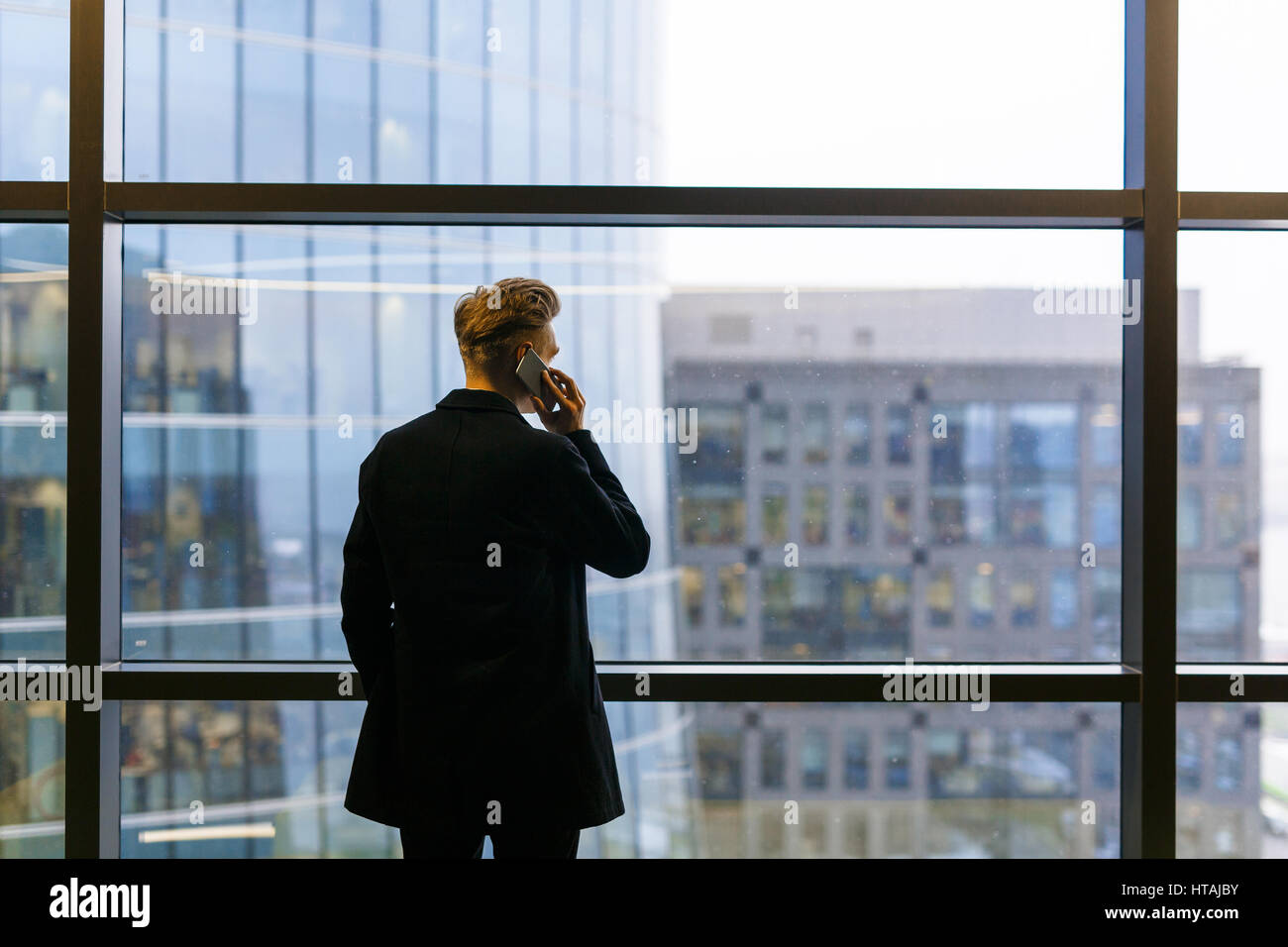 Back view of young agent consulting someone by cellphone Stock Photo ...
