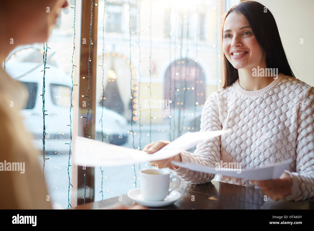 Portrait of smiling young woman at job interview in cafe, handing her ...