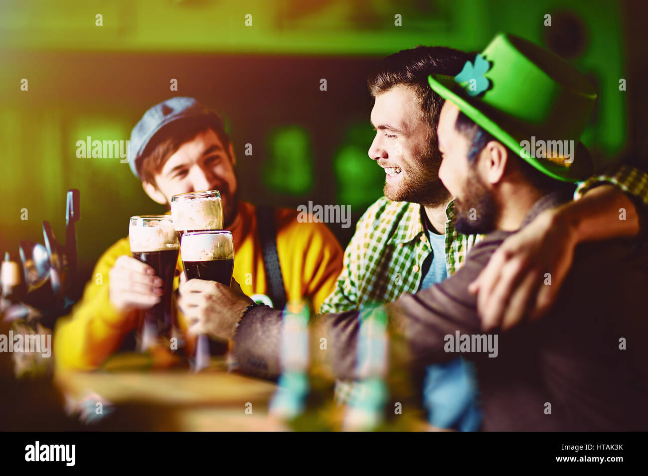 Three slightly drunk friends dressed in traditional green enjoying dark ...