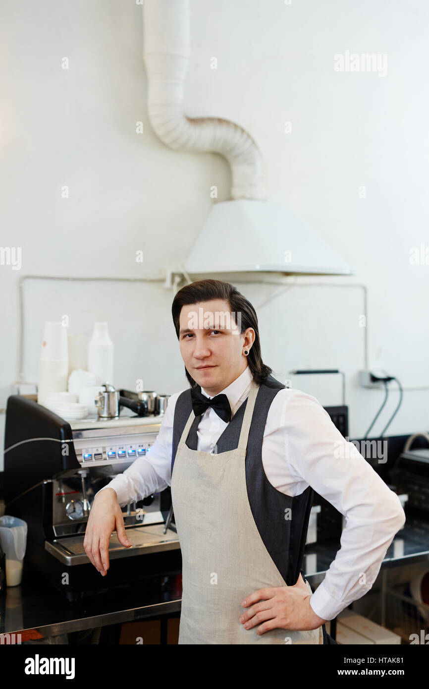 Elegant barman in apron standing by coffee-machine Stock Photo - Alamy