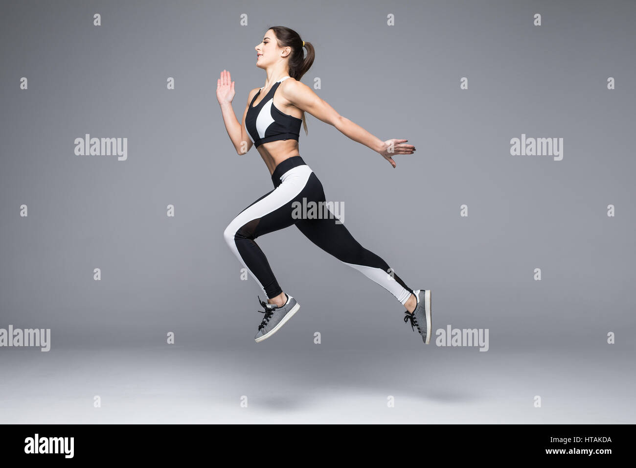 Side view of sporty young woman jumping isolated on grey background ...
