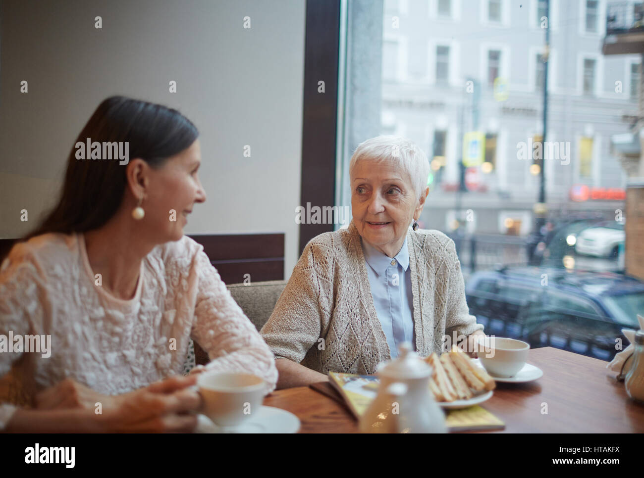 Two female buddies talking in cafe by snack Stock Photo - Alamy