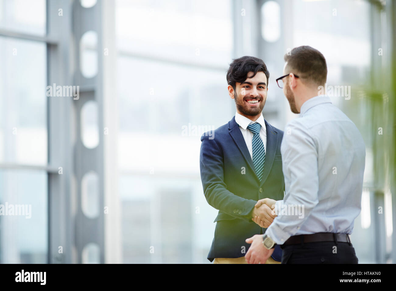 Happy businessman greeting new co-worker after introducing Stock Photo ...