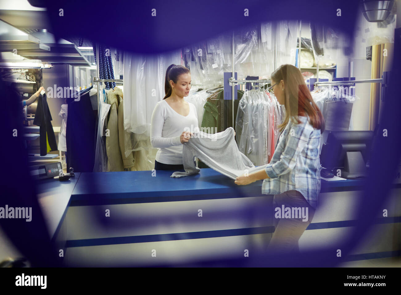 Dry cleaner showing her client clean pullover by counter Stock Photo ...