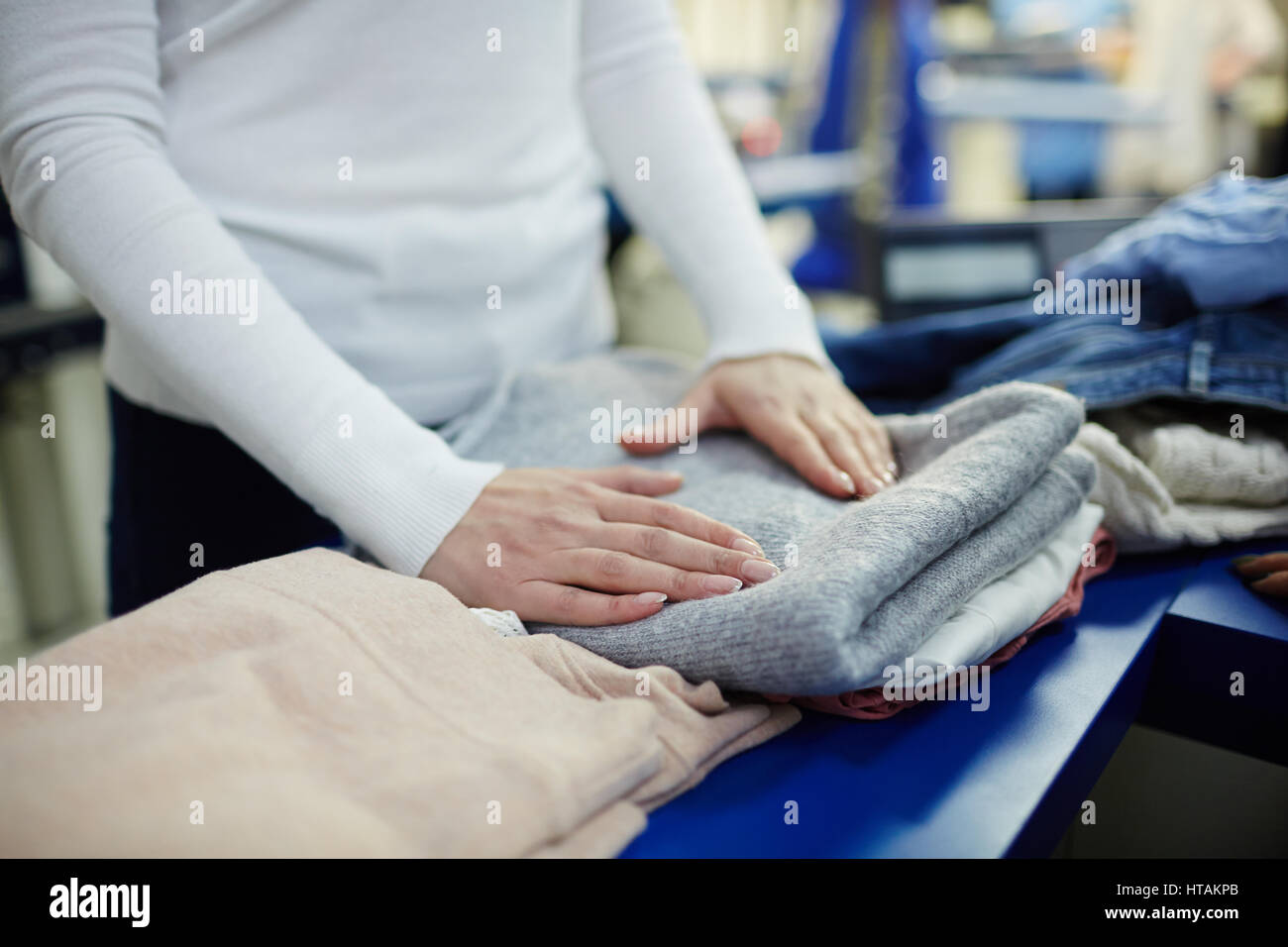 Woman folding clean clothes in dry-cleaning workshop Stock Photo - Alamy