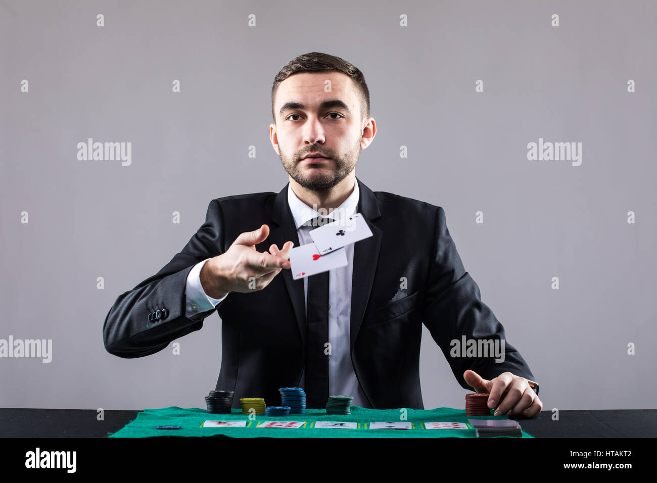 Poker player, on a grey background, throwing two ace cards Stock Photo ...