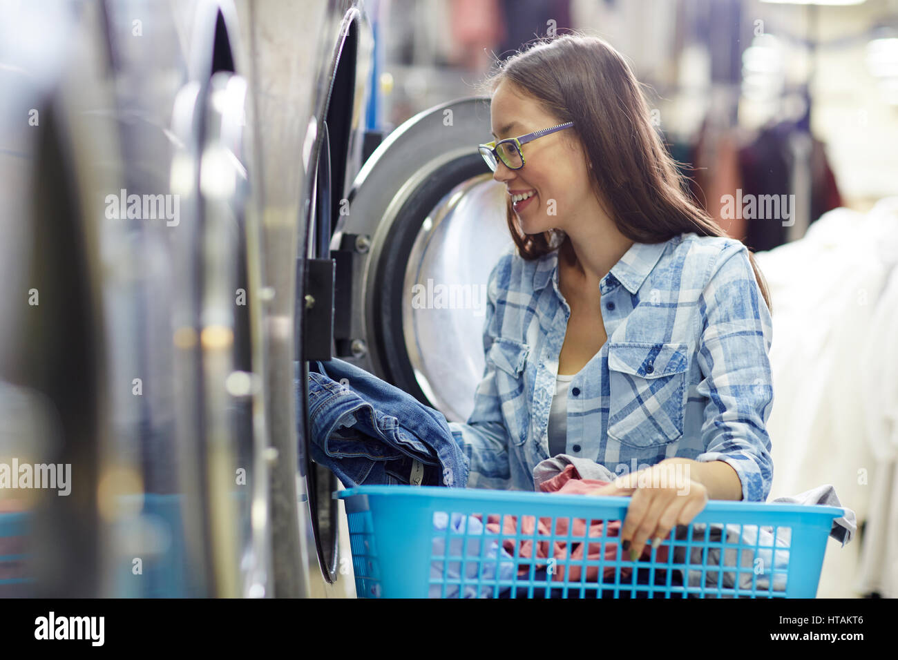 Young maid or housekeeper washing clothes in automatic machine Stock ...