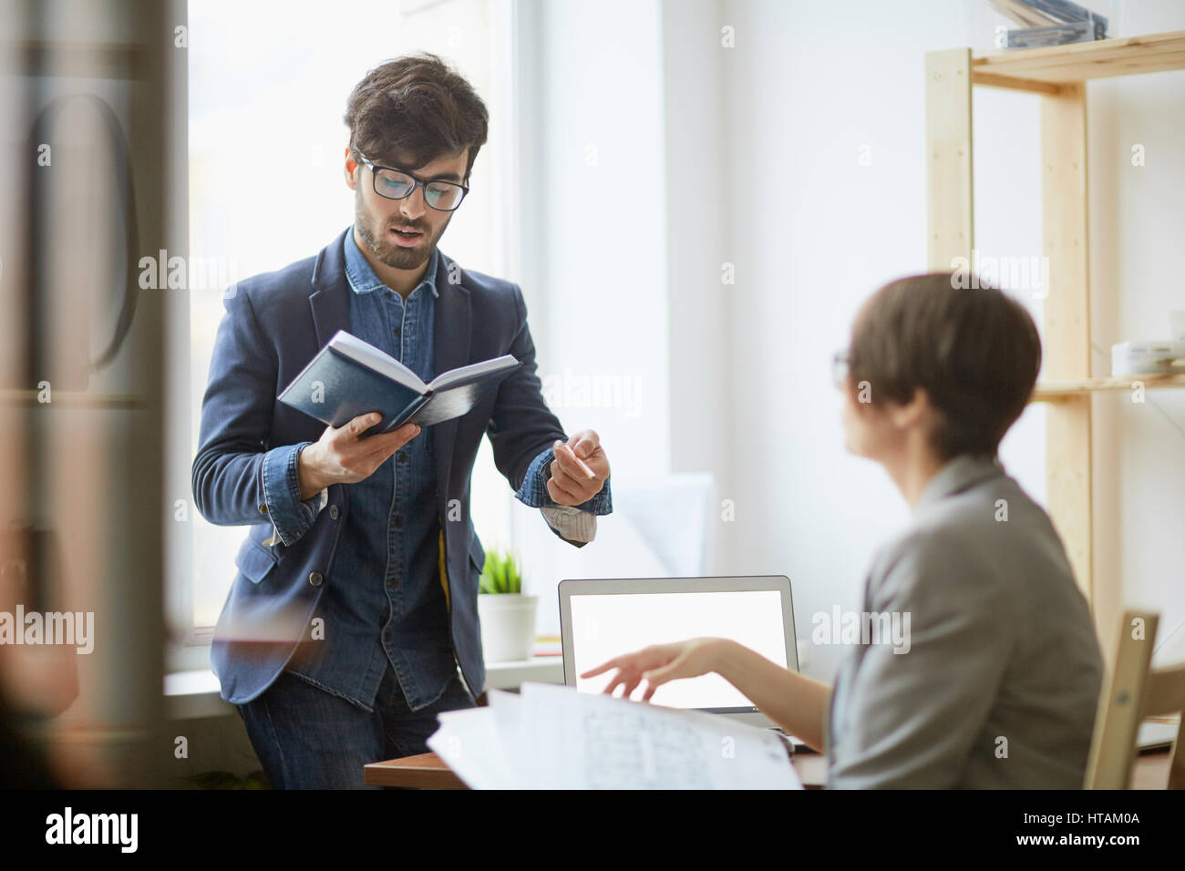Portrait of contemporary young manager standing against window ...