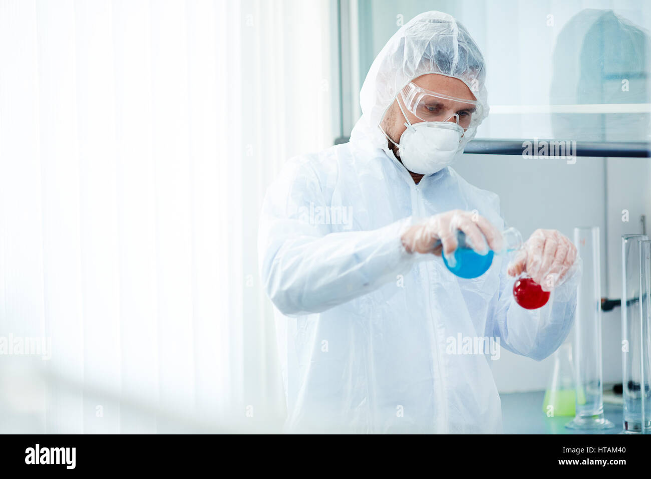 Researcher in protective clothes mixing two liquid substances in lab ...