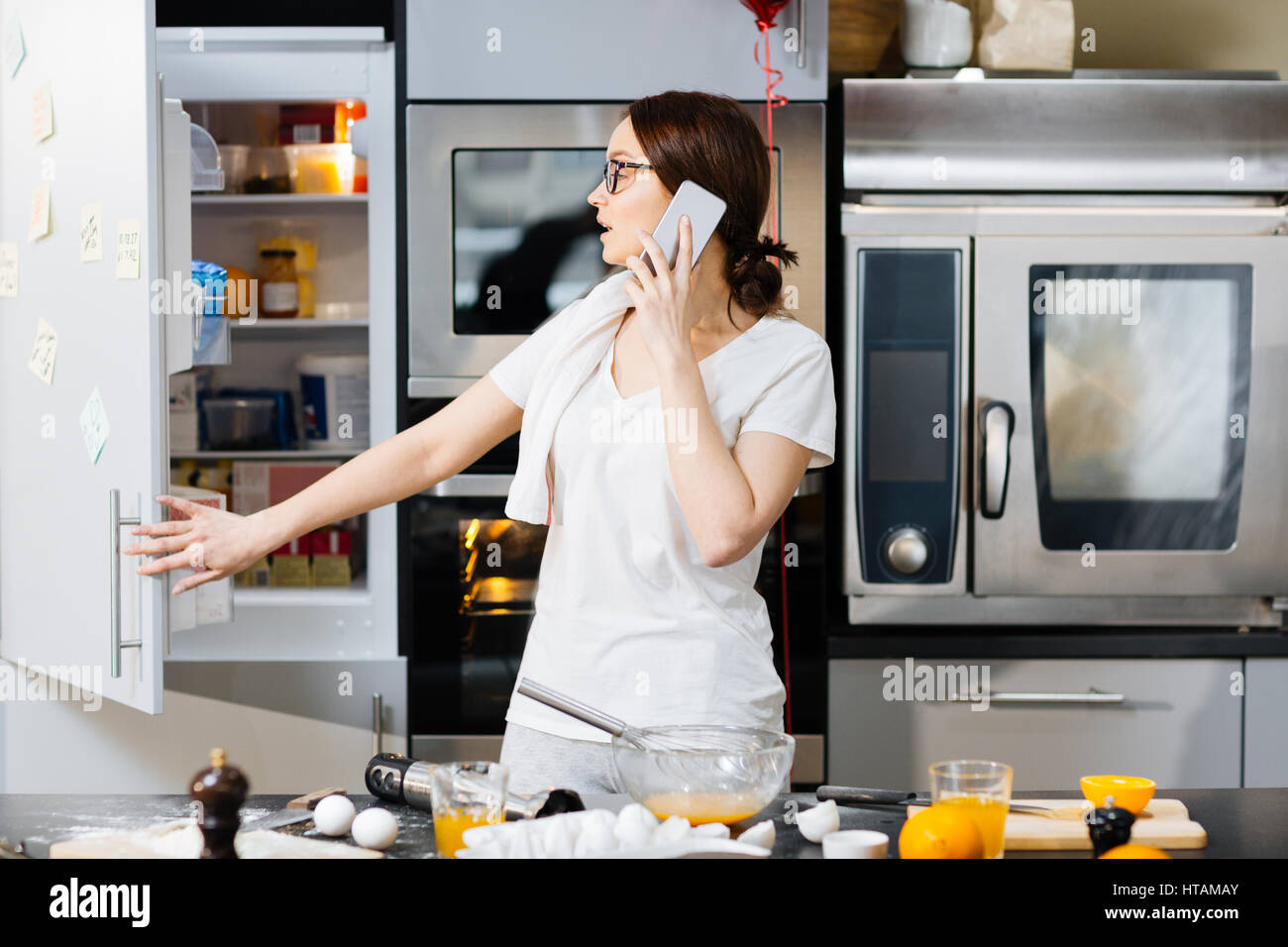 Housewife talking on cellphone and opening refrigerator Stock Photo - Alamy