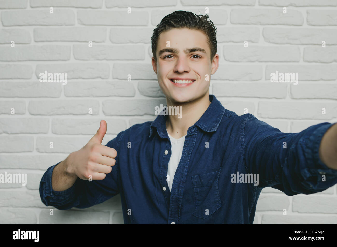 Portrait of young goodlooking man against white brickwall Stock Photo ...