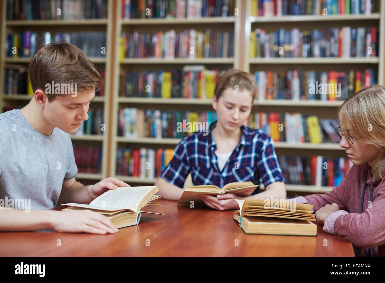 Adolescent people with books reading in library Stock Photo - Alamy
