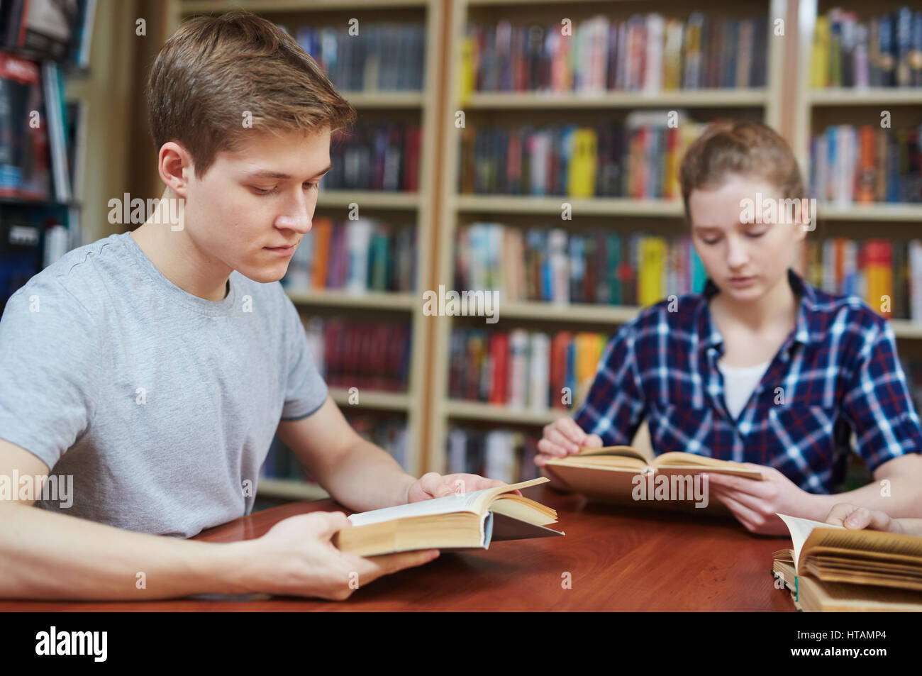 Guy and girl reading in library Stock Photo - Alamy