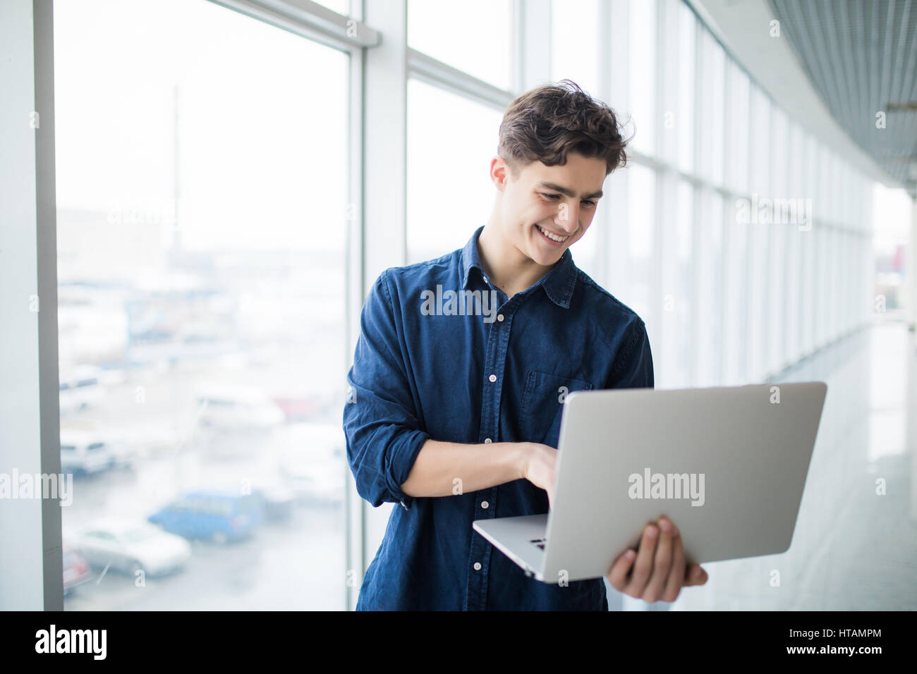 Handsome young man man holding and use a laptop in hall Stock Photo - Alamy