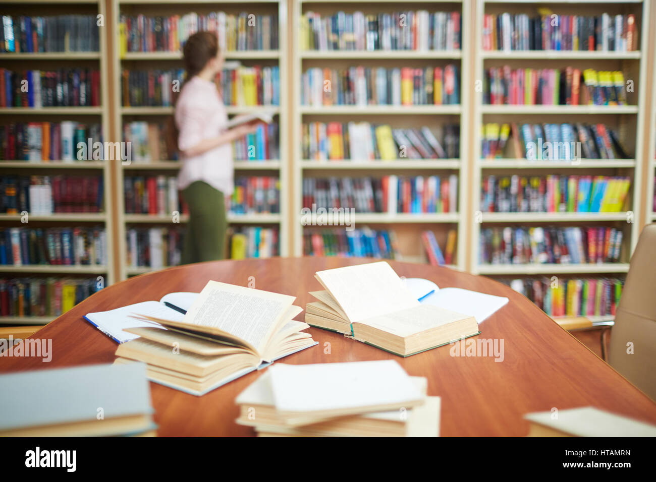 Open books on desk and human by bookshelf on background Stock Photo - Alamy