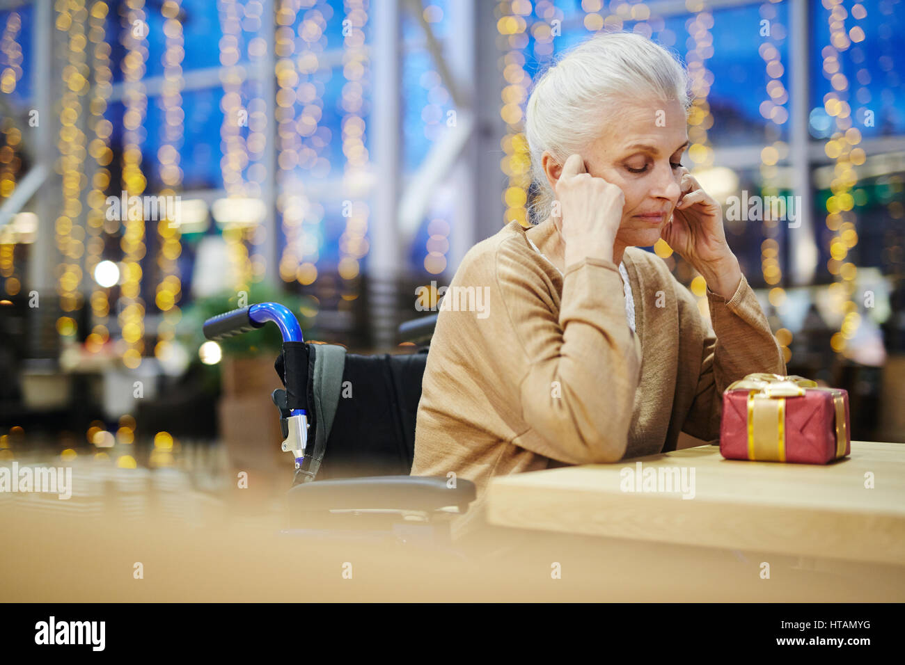 Alone female in wheelchair looking at gift-box Stock Photo - Alamy