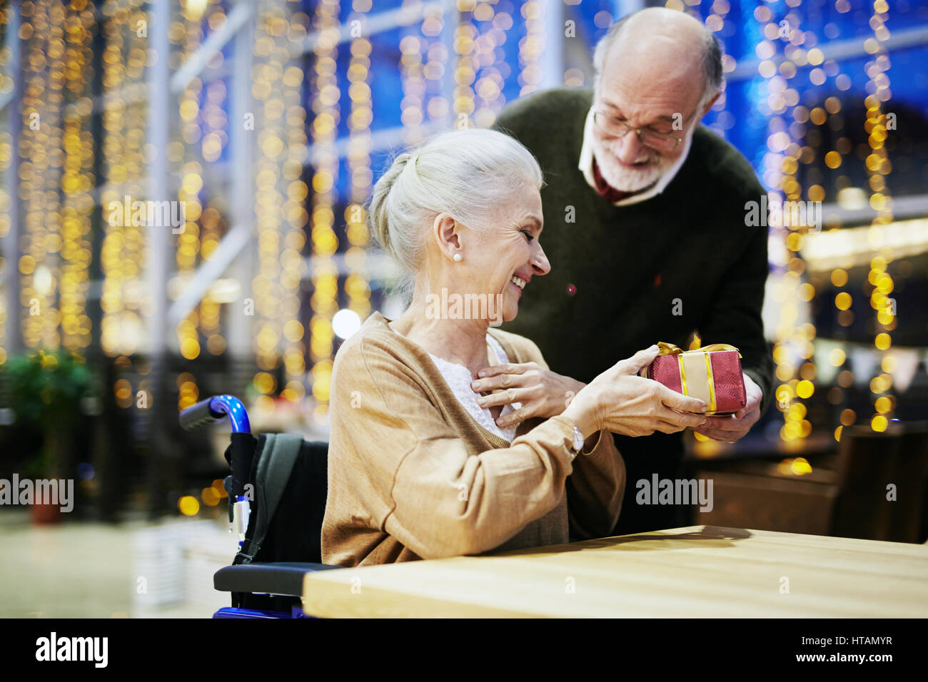 Disabled female taking small gift-box from her husband Stock Photo - Alamy