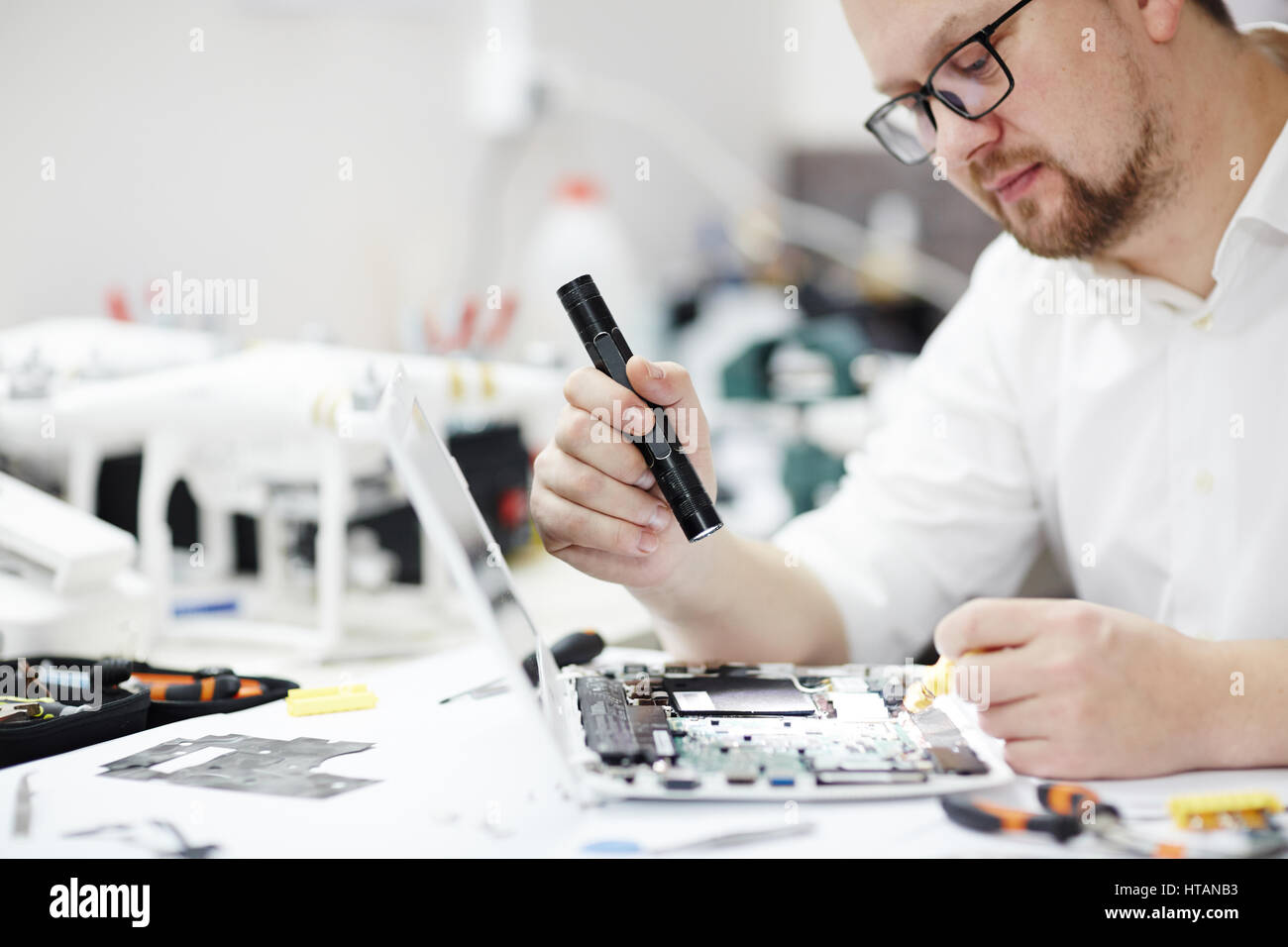 Side view portrait of male service worker opening disassembled computer ...