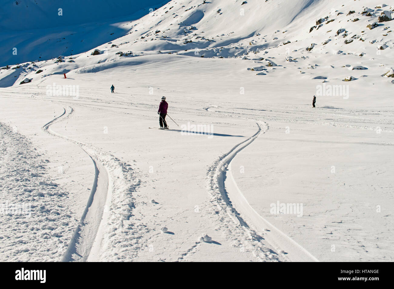 Skiers on a ski slope piste in winter alpine mountain resort Stock ...