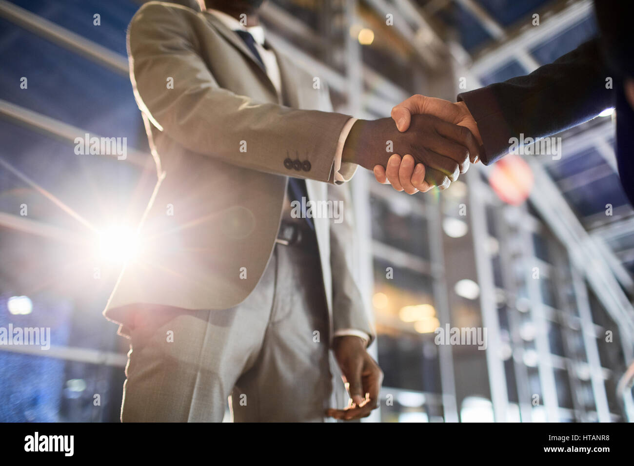Two successful traders handshaking on background of modern construction ...