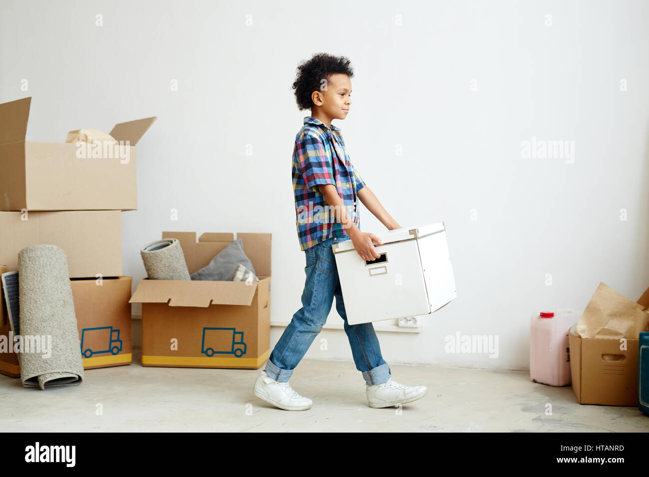 Little boy carrying big box during relocation Stock Photo - Alamy