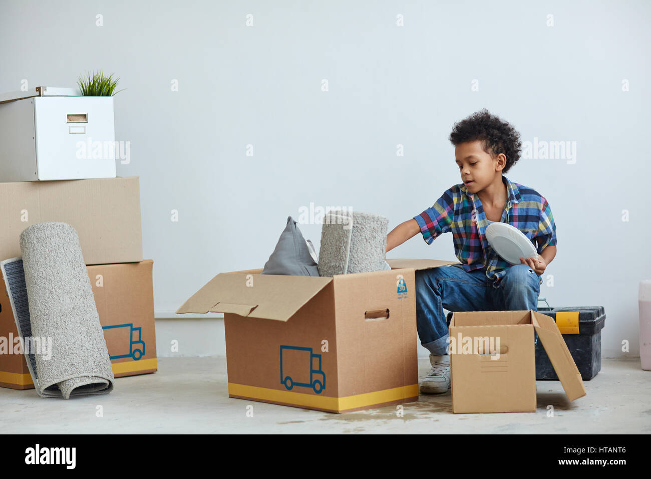 Adorable youngster taking out plates out of carton box Stock Photo - Alamy