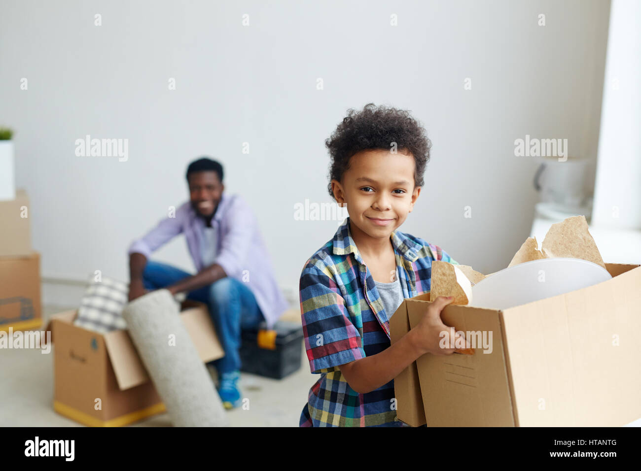 Cute boy helping with unpacking things and boxes Stock Photo - Alamy