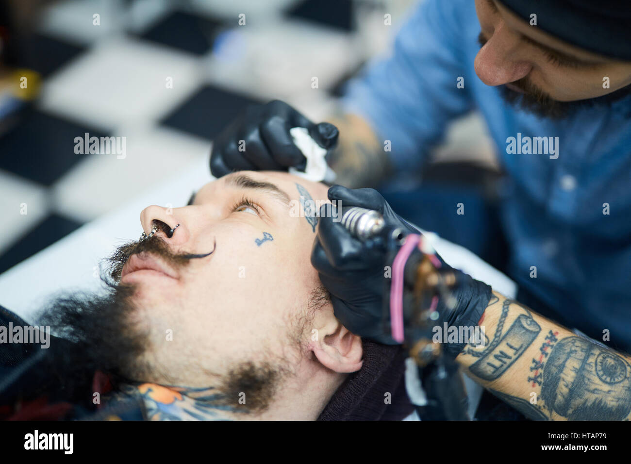 Master of tattoo art drawing on man face Stock Photo - Alamy
