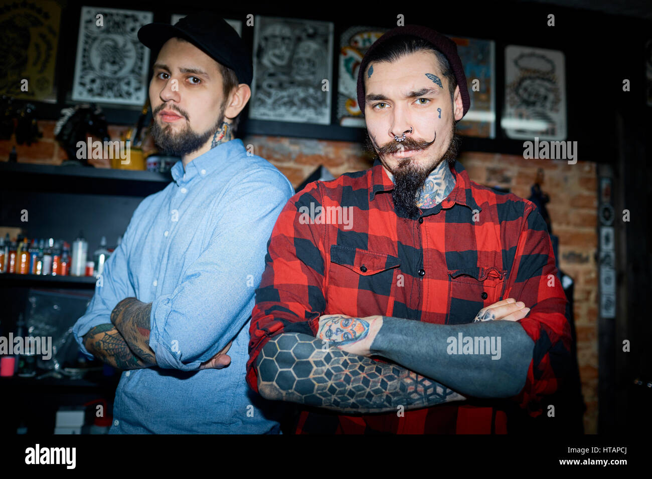 Owner of tattoo salon and his colleague looking at camera Stock Photo ...