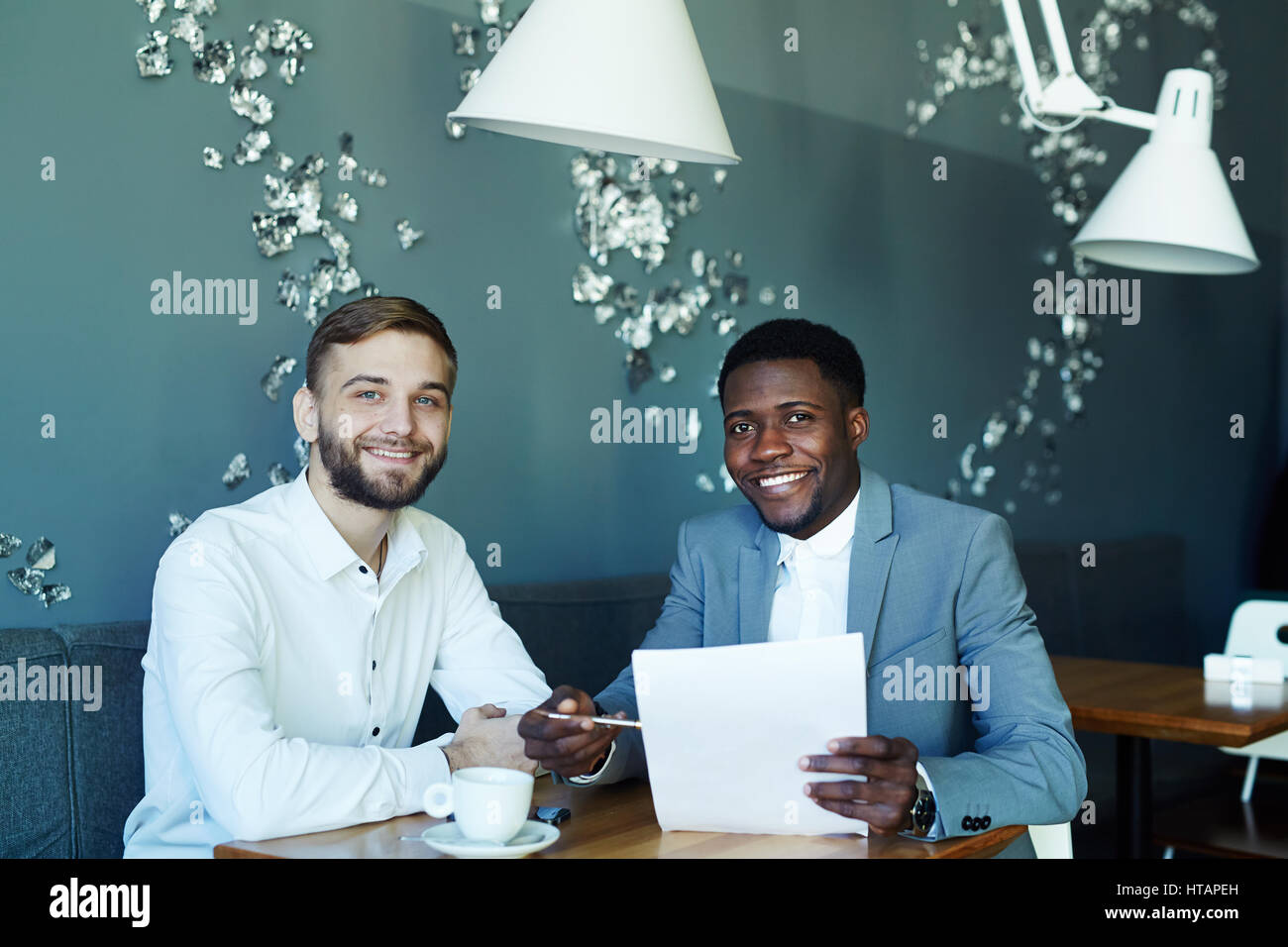 Portrait of two handsome business people, one of them African, sitting ...
