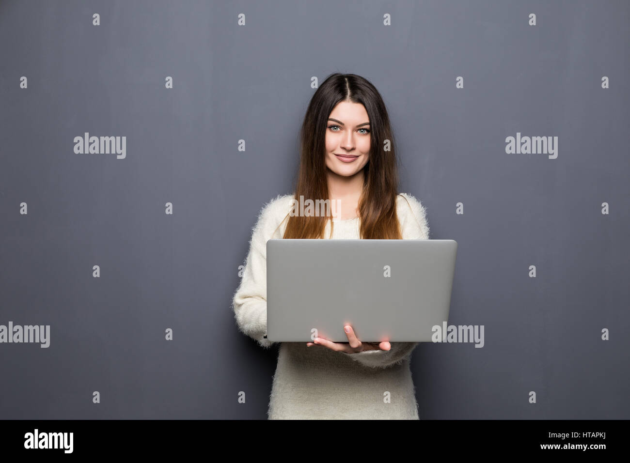 young woman standing on light gray background and holding laptop Stock ...