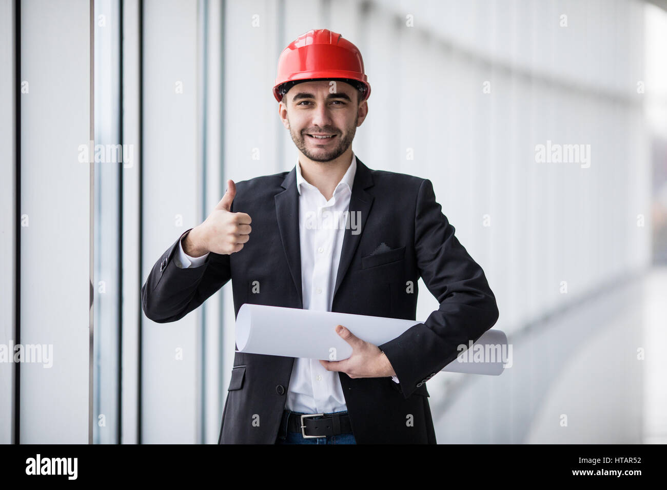 Young engineer with thumbs up indoors near big windows Stock Photo - Alamy