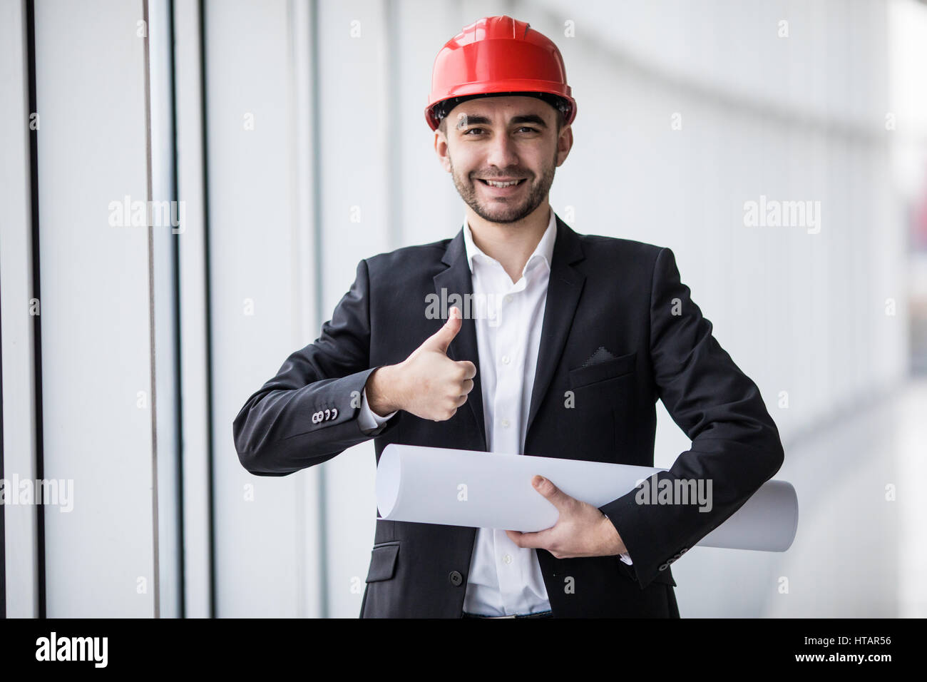 Young engineer with thumbs up indoors near big windows Stock Photo - Alamy